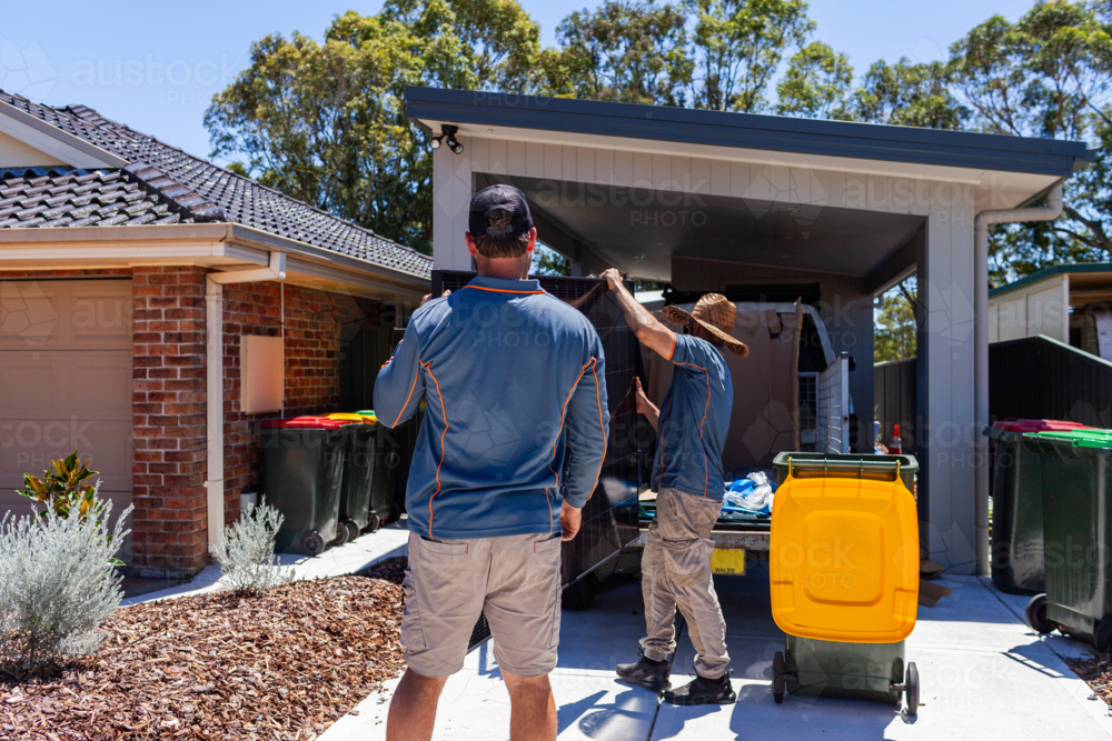 Image of Pair of Aussie tradies unloading solar panels from back of ...