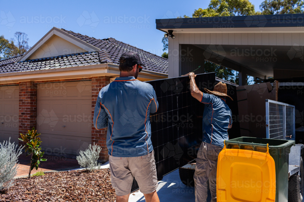 Image of Pair of Aussie tradiesmen unloading solar panels from back of ...