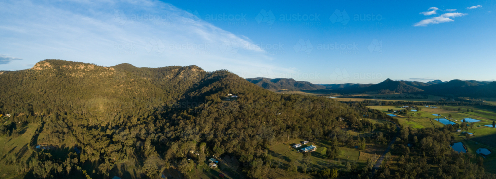 Image of Panorama of green sunlit farm paddock and mountain landscape ...
