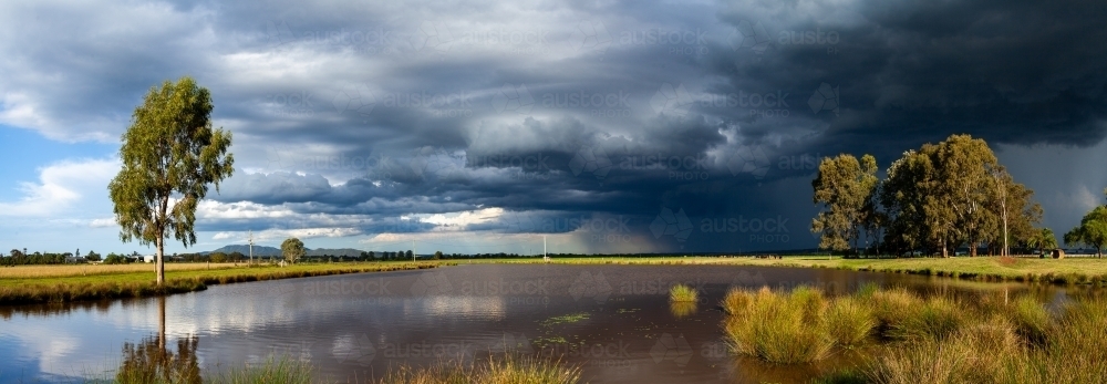 Image of panoramic view of dark stormy rain clouds incoming over sunlit ...