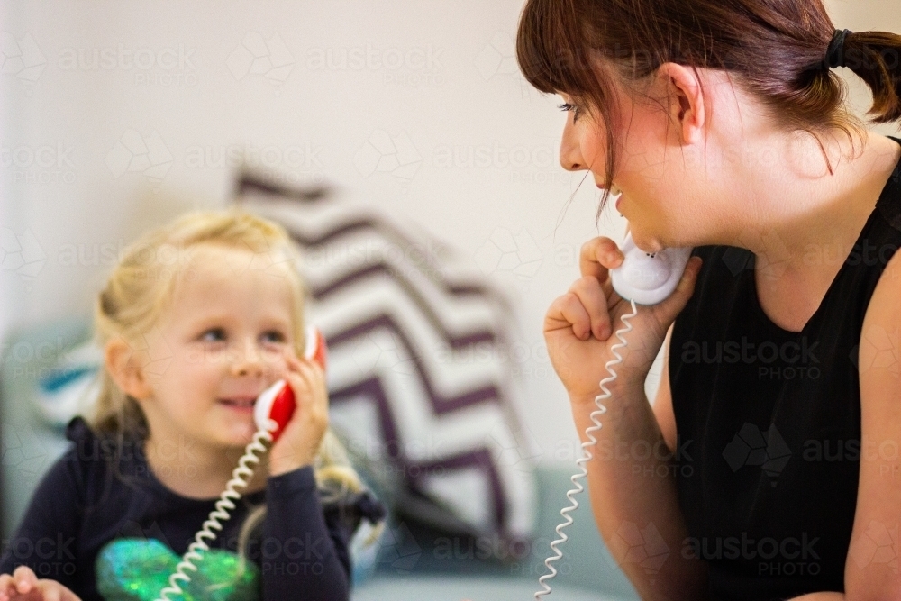 Image of Parent and child talking together on toy telephone - Austockphoto