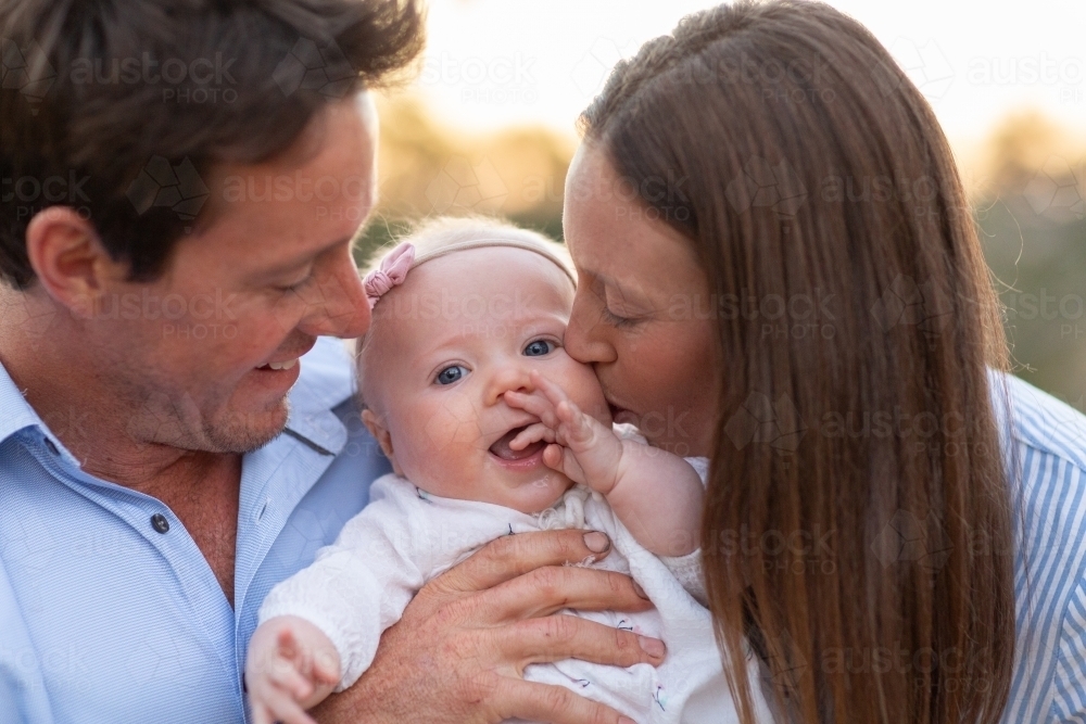 Image of Parents cuddling their baby girl - Austockphoto