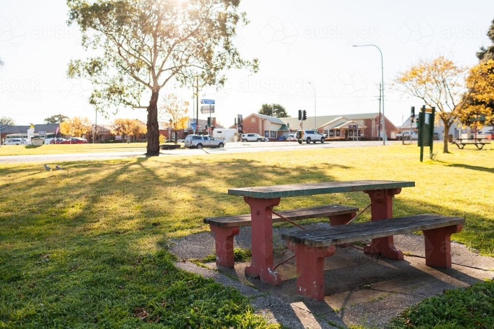 Image of Park bench seat in sunlit park beside busy intersection in ...
