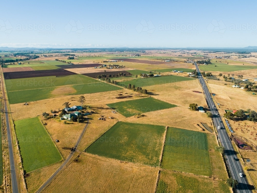 Image of patchwork of farm paddocks beside highway - Austockphoto