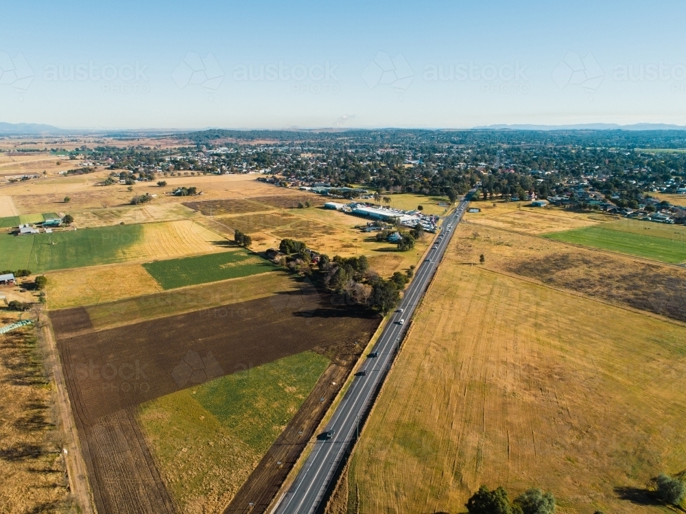 Image of patchwork of farm paddocks beside highway - Austockphoto