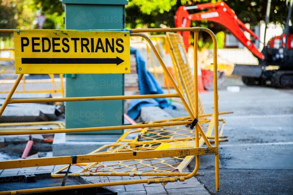 Image of Pedestrians this way sign with barrier fence at worksite ...