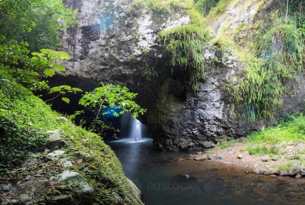 Image of Peering in to a hidden waterfall in a cave - Austockphoto