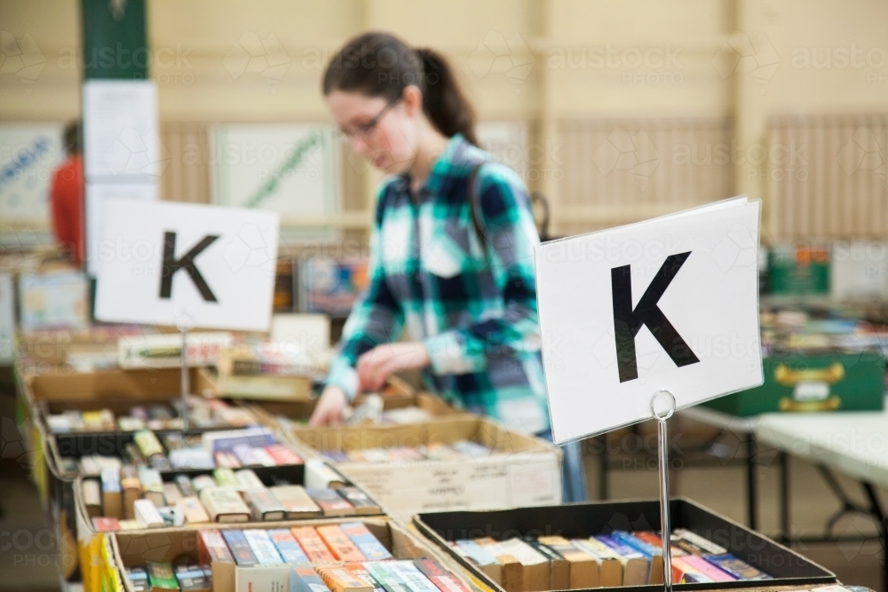 Image of People looking through books at a book fair sale - Austockphoto