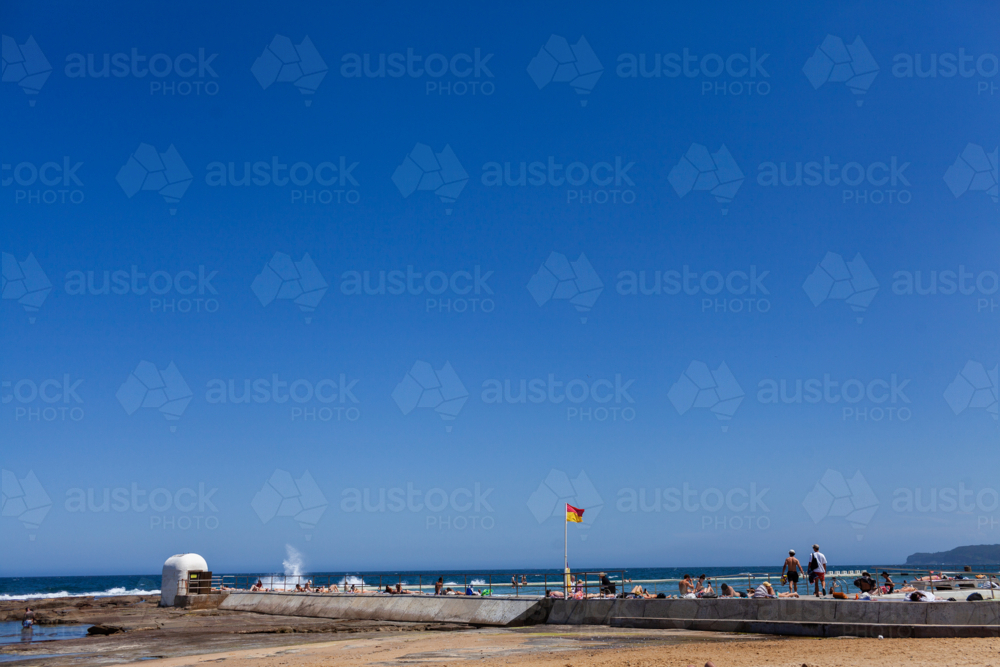 Image of People relaxing and sunbathing along ocean pool wall at ...