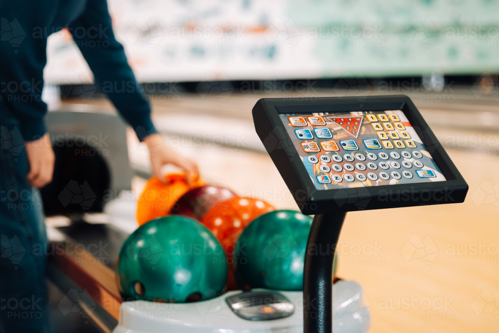 Image of Person collecting bowling ball from pinsetter machine ...
