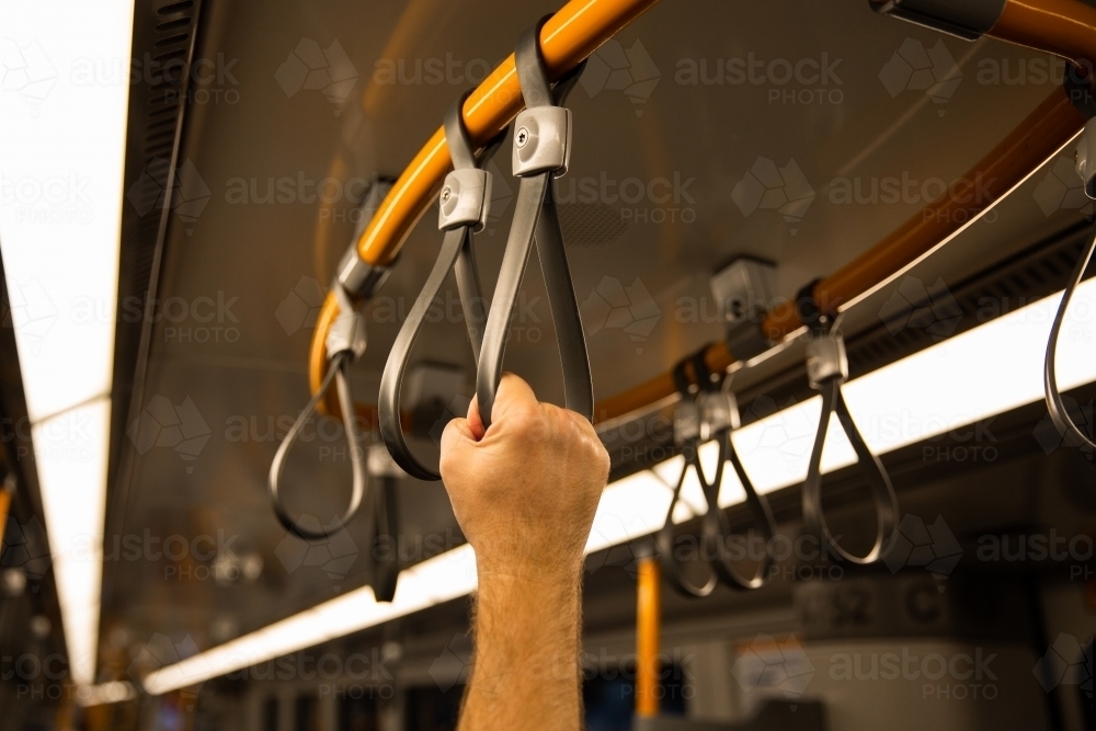 Image of person holding on to a handle in a train carriage - Austockphoto