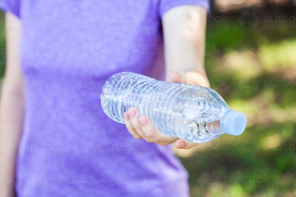 Image of Person holding out plastic water bottle with water in it ...