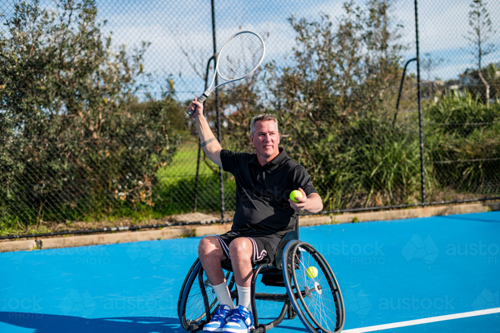 Image of Person in wheelchair about to toss a tennis ball on a bright ...