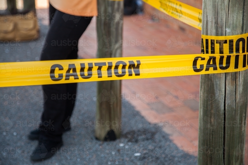 Image of Person leaning on pole inside area taped off with caution ...
