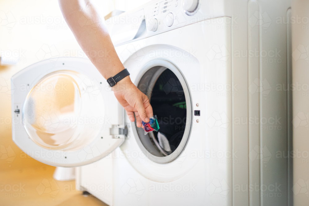 Image of Person placing laundry detergent capsule in front loader ...
