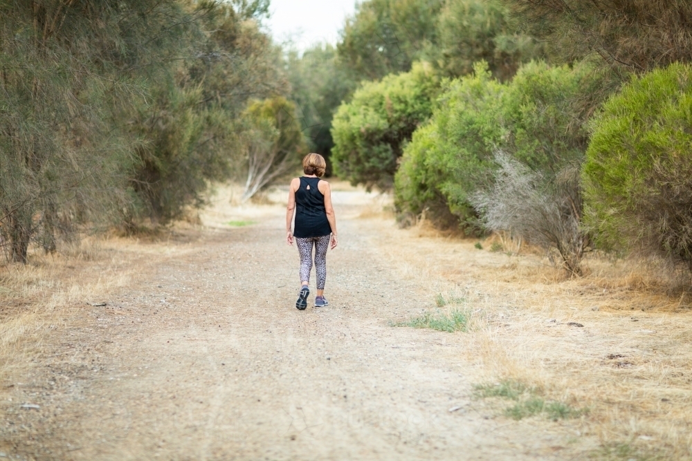 Image of person walking away down country lane - Austockphoto