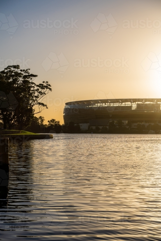 Image of Perth AFL Stadium over water at sunset - Austockphoto