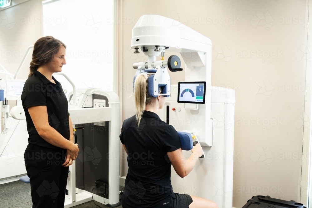 Image of Physio directing woman using rehabilitation exercise machine ...