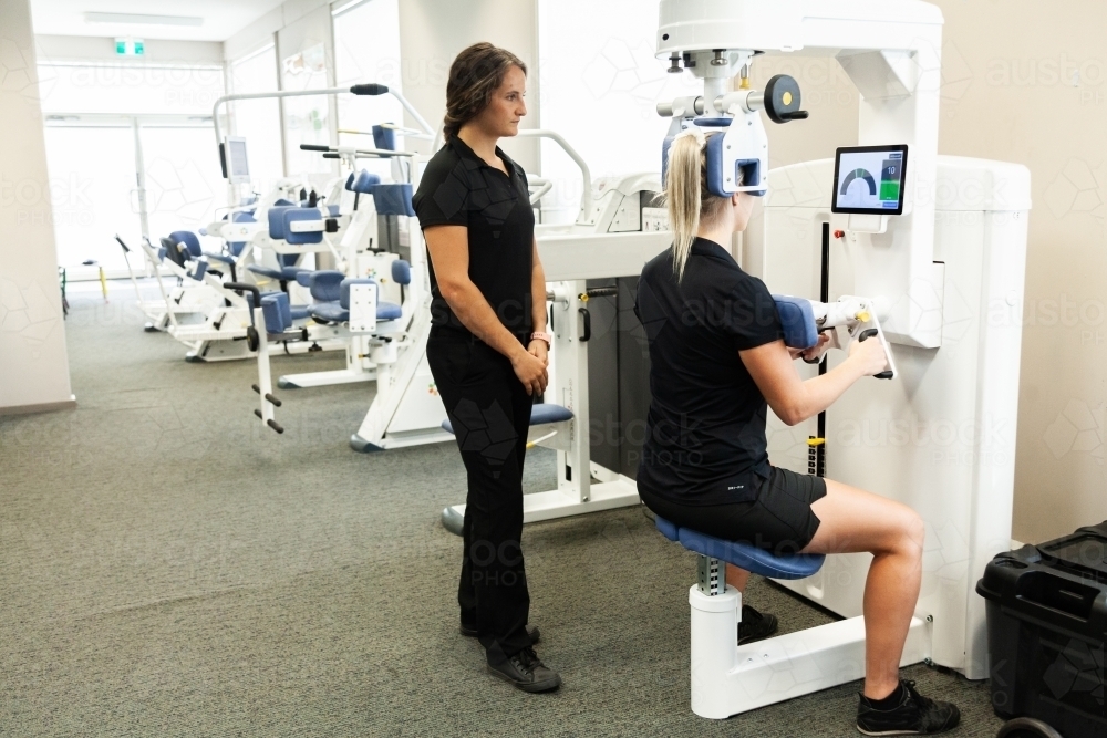 Image of Physio directing woman using rehabilitation exercise machine ...