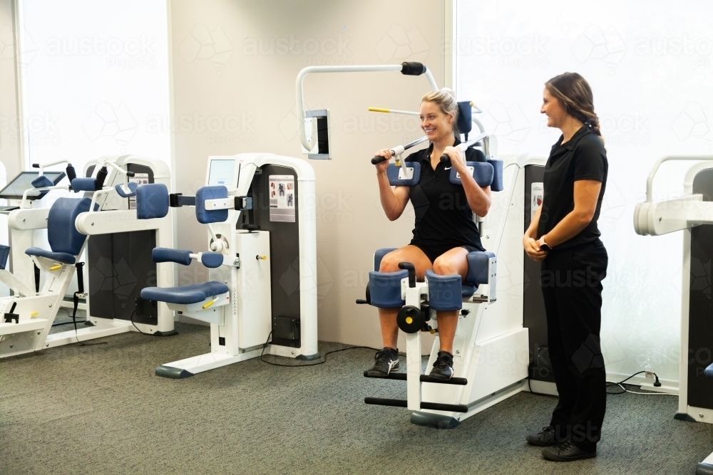 Image of Physio directing woman using rehabilitation exercise machine ...