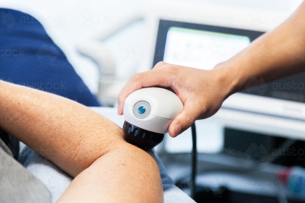 Image of Physio using massage head on shockwave therapy machine ...