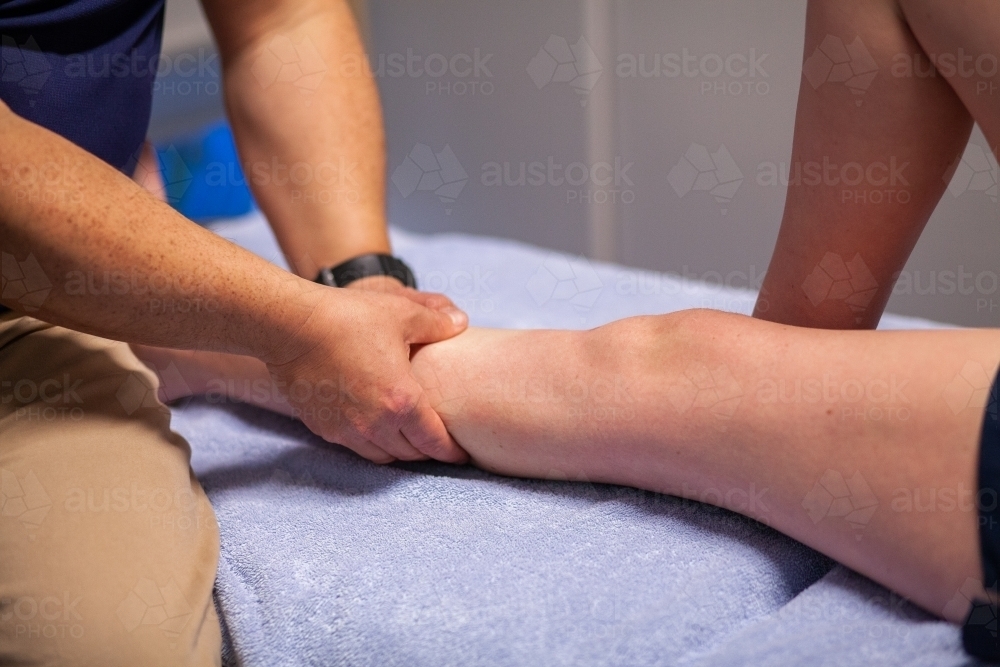 Image of Physio working on leg of teen girl with injury helping with ...