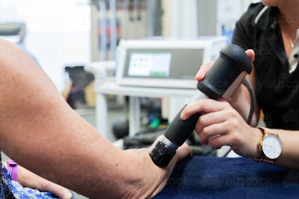 Image of Physiotherapist using shockwave therapy machine on clients arm ...