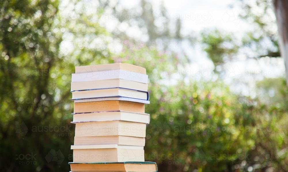 Image of Pile of books outside with green bokeh background - Austockphoto