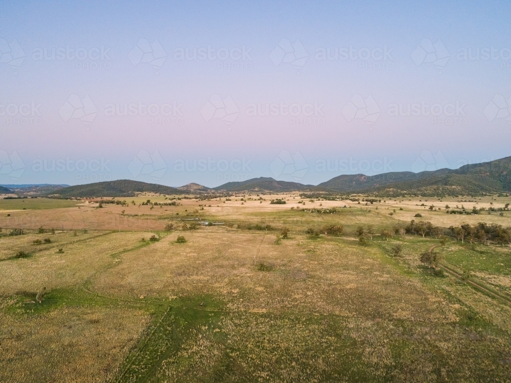 Image of pink dusk light over wide open spaces of pastoral farmland ...
