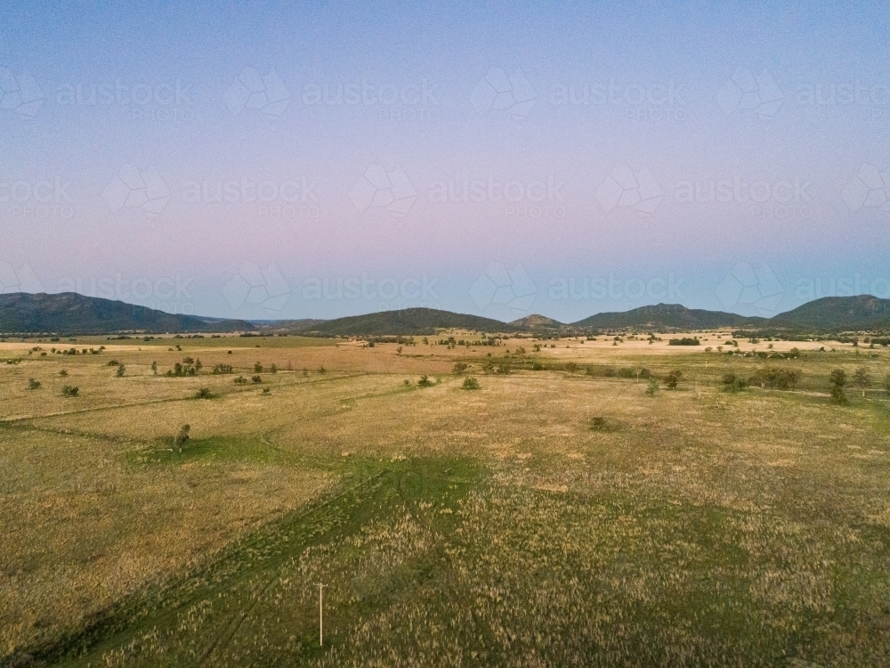 Image of pink dusk light over wide open spaces of pastoral farmland ...