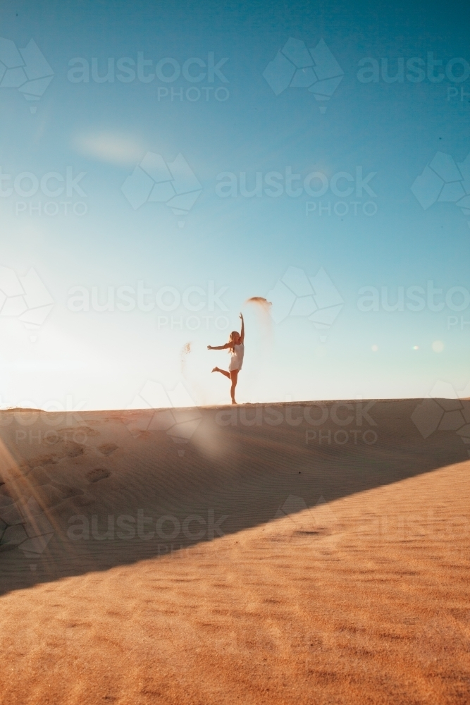 Image of Playful young adult Tossing Sand on Sunlit Dunes during a ...