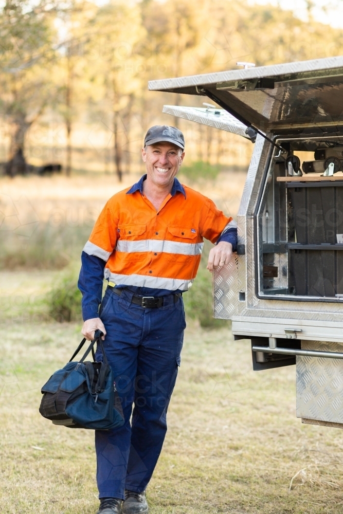 Image of plumber tradie leaning on back of work ute - Austockphoto