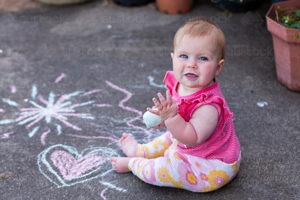 Image of Portrait of a baby sitting on concrete in backyard drawing ...