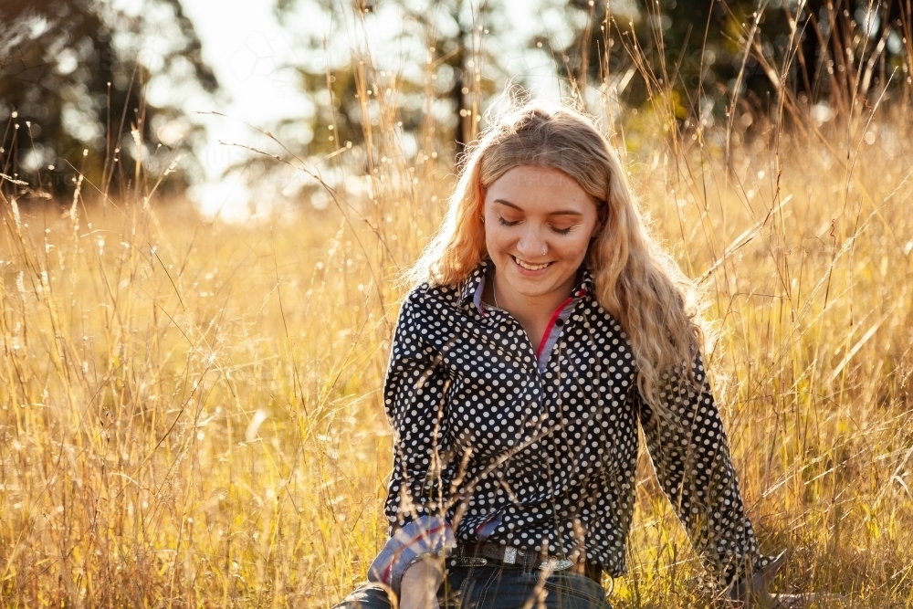 Image of Portrait of a happy young country woman sitting in golden ...