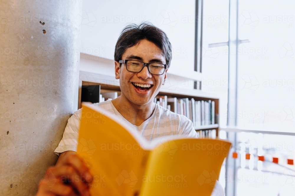 Image of Portrait of a smiling man holding an opened yellow book with a ...
