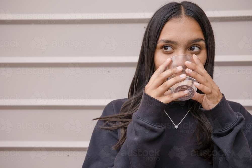Image of Portrait of a young, first nations woman drinking a glass of ...