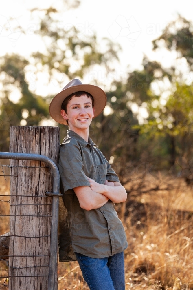 Image of Portrait of a young teen boy in hat leaning back on gate in ...