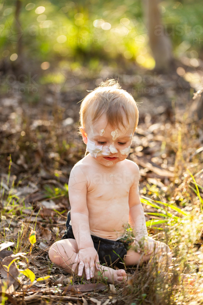 Image of Portrait of aboriginal baby boy with ochre on face and feeding ...