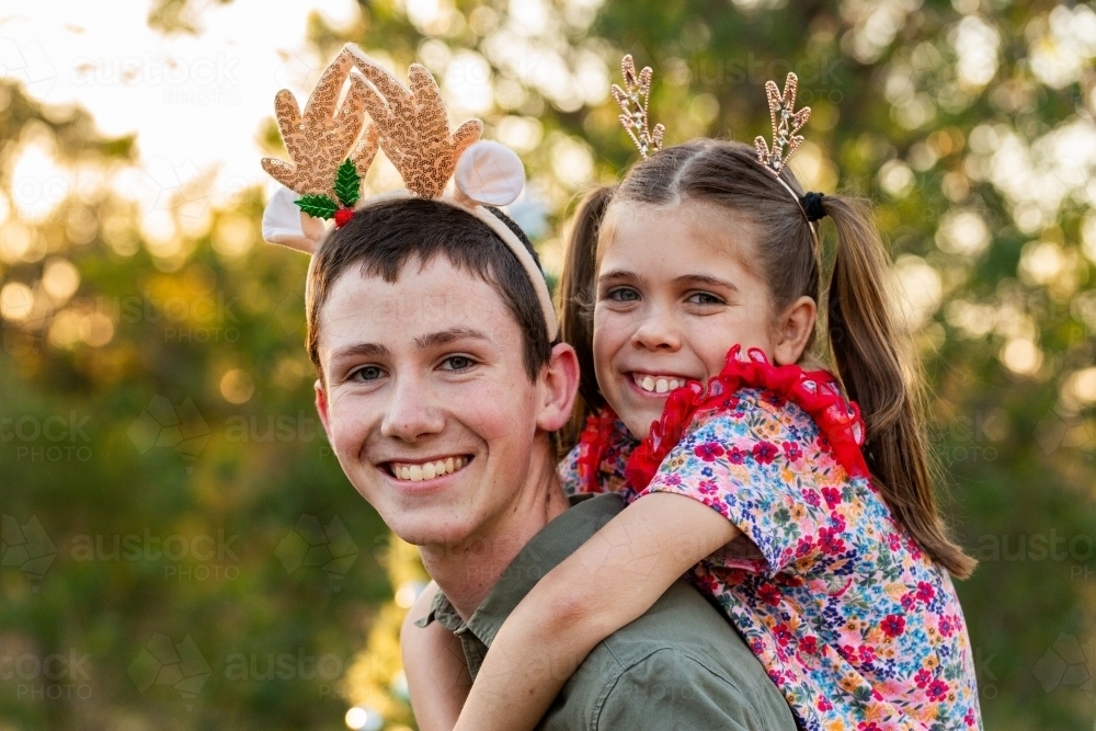 Image of Portrait of brother giving sister piggyback ride outside at ...