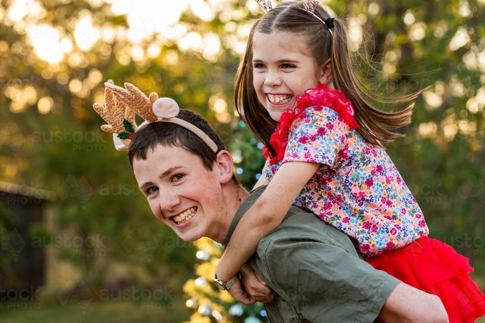 Image of Portrait of brother giving sister piggyback ride outside at ...