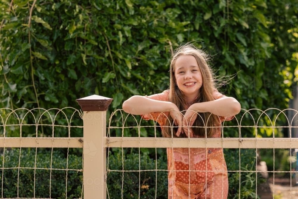 Image of Portrait of cheerful pre-teen girl leaning on wire fence in ...