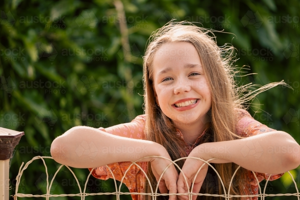 Image of Portrait of cheerful pre-teen girl leaning on wire fence in ...