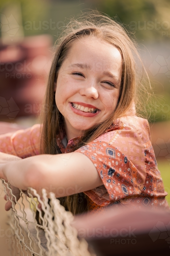 Image of Portrait of cheerful pre-teen girl leaning on wire fence in ...
