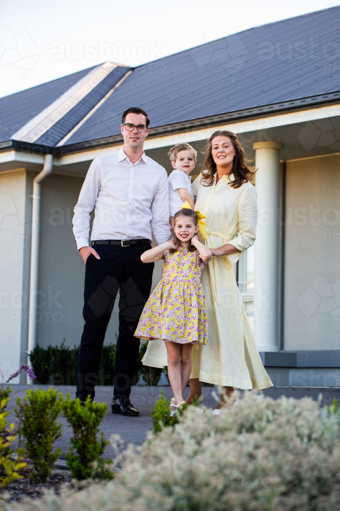 Image of Portrait of family of four standing together outside home dad ...