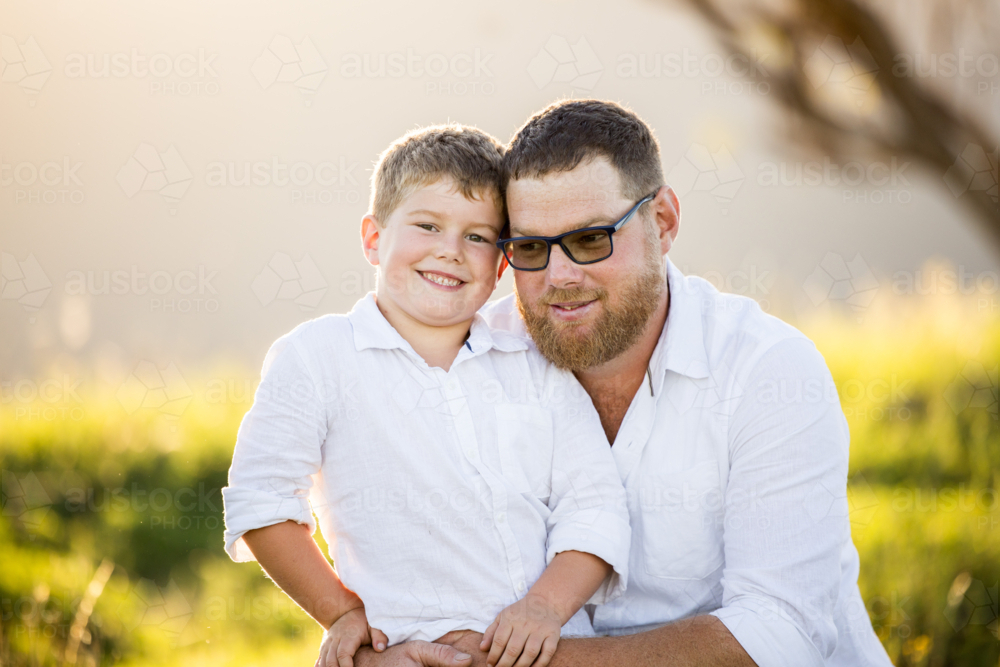 Image of Portrait of father and son sitting together on log on ...