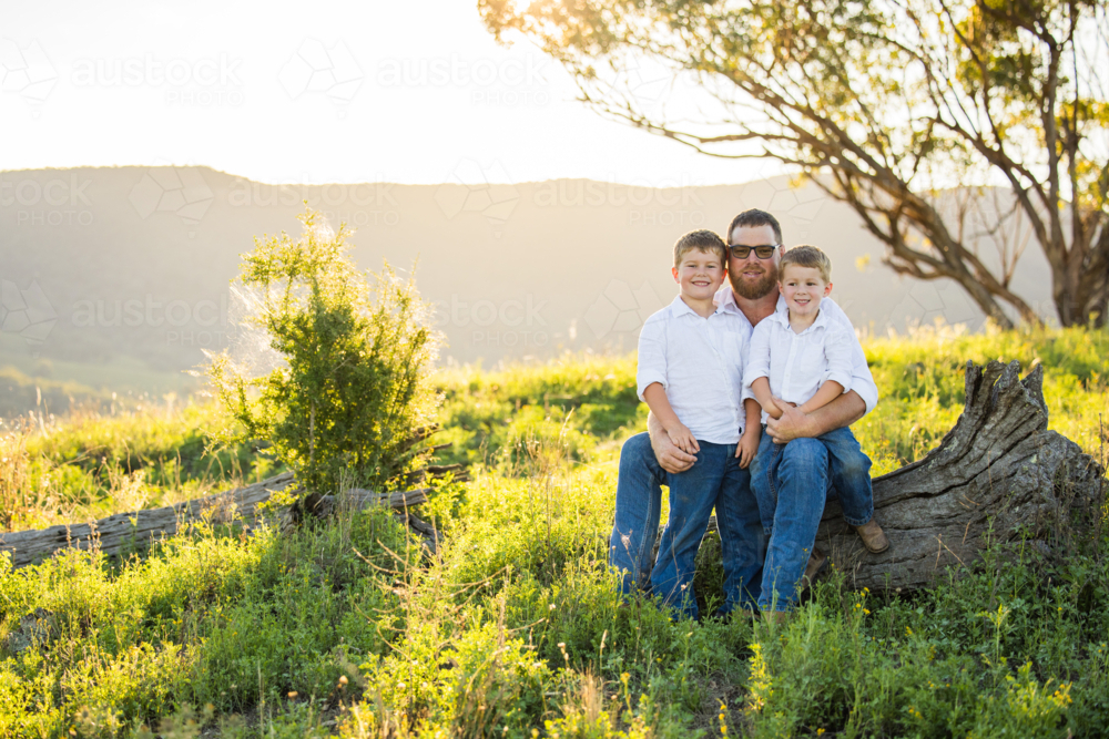 Image of Portrait of father and sons sitting together on log on ...