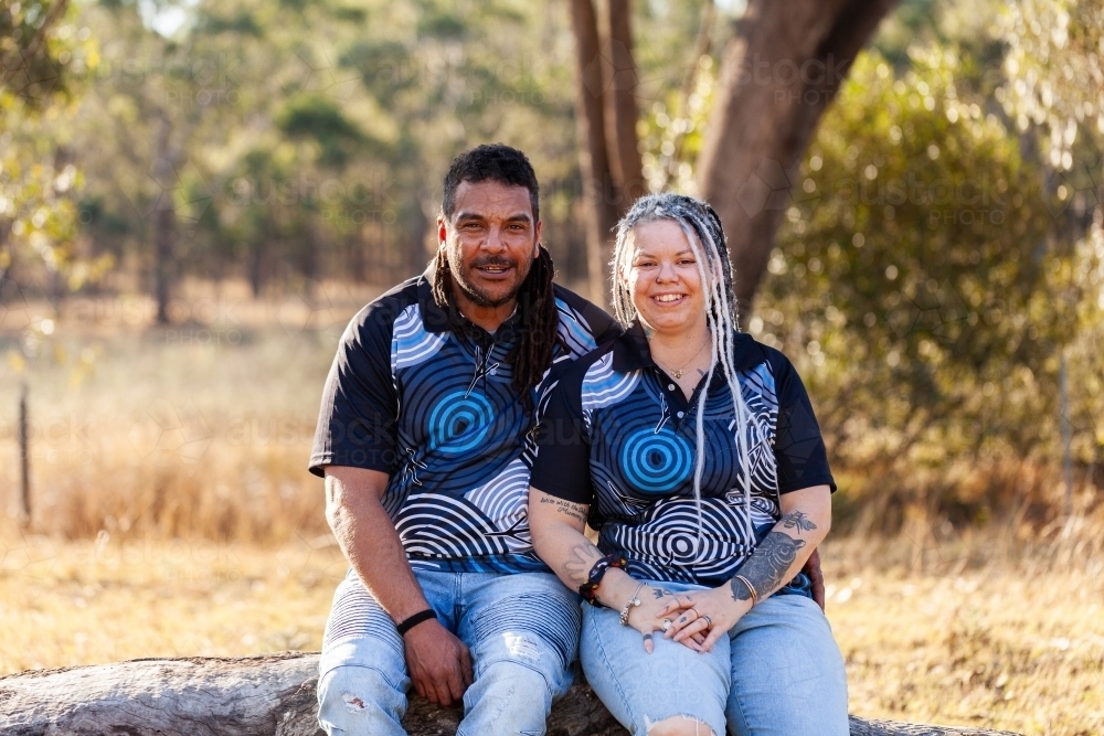 Image of Portrait of happy aboriginal couple sitting together on log ...