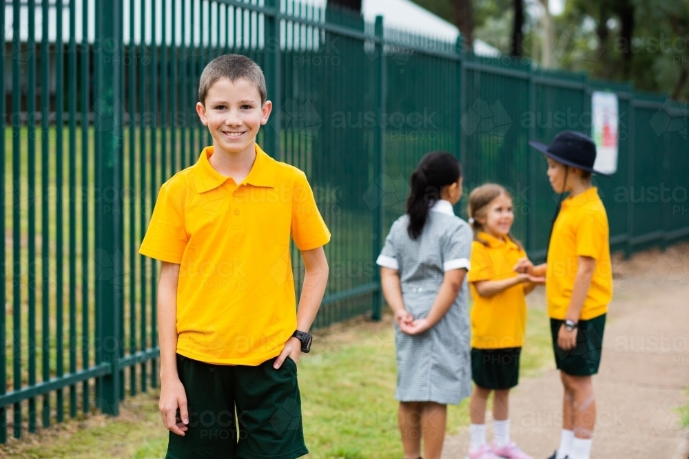 Image of Portrait of happy Aussie school boy near school fence ...