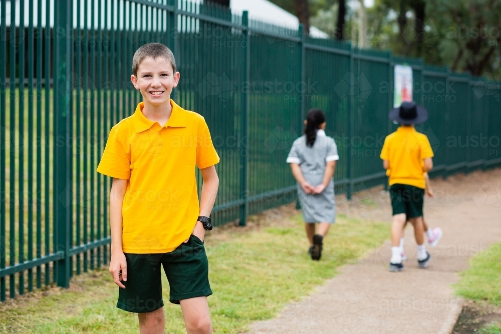 Image of Portrait of happy Aussie school boy near school fence ...