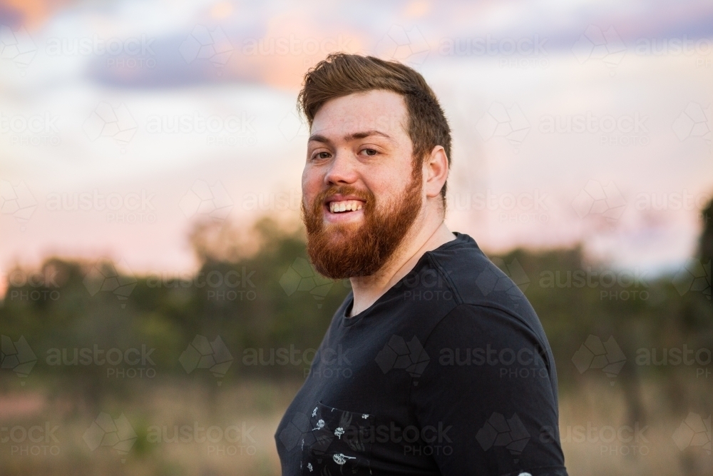 Image of Portrait of happy bearded australian man outside at dusk ...